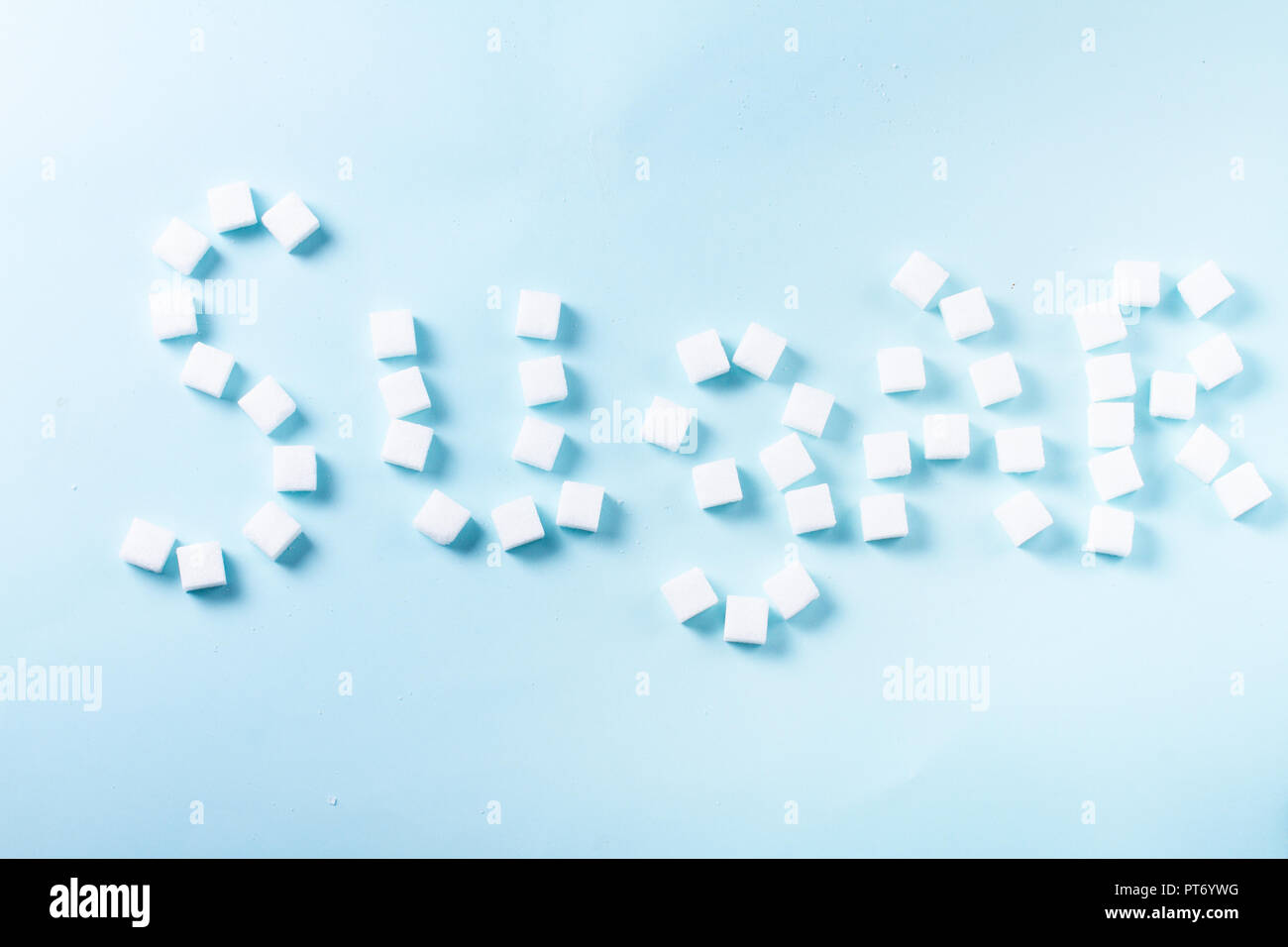 Sugar word in sugar cubes on blue background Stock Photo - Alamy
