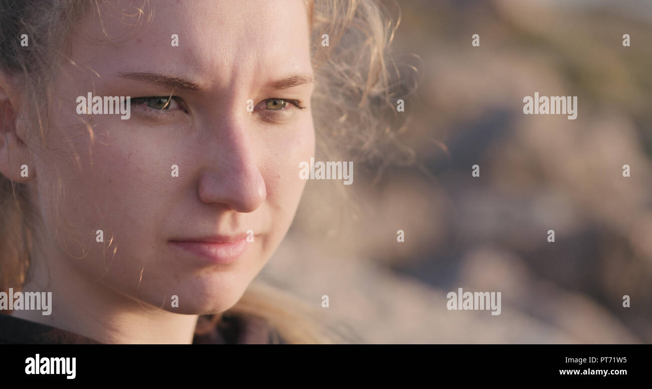 young female closeup portrait sitting on a seashore with thoughtful ...