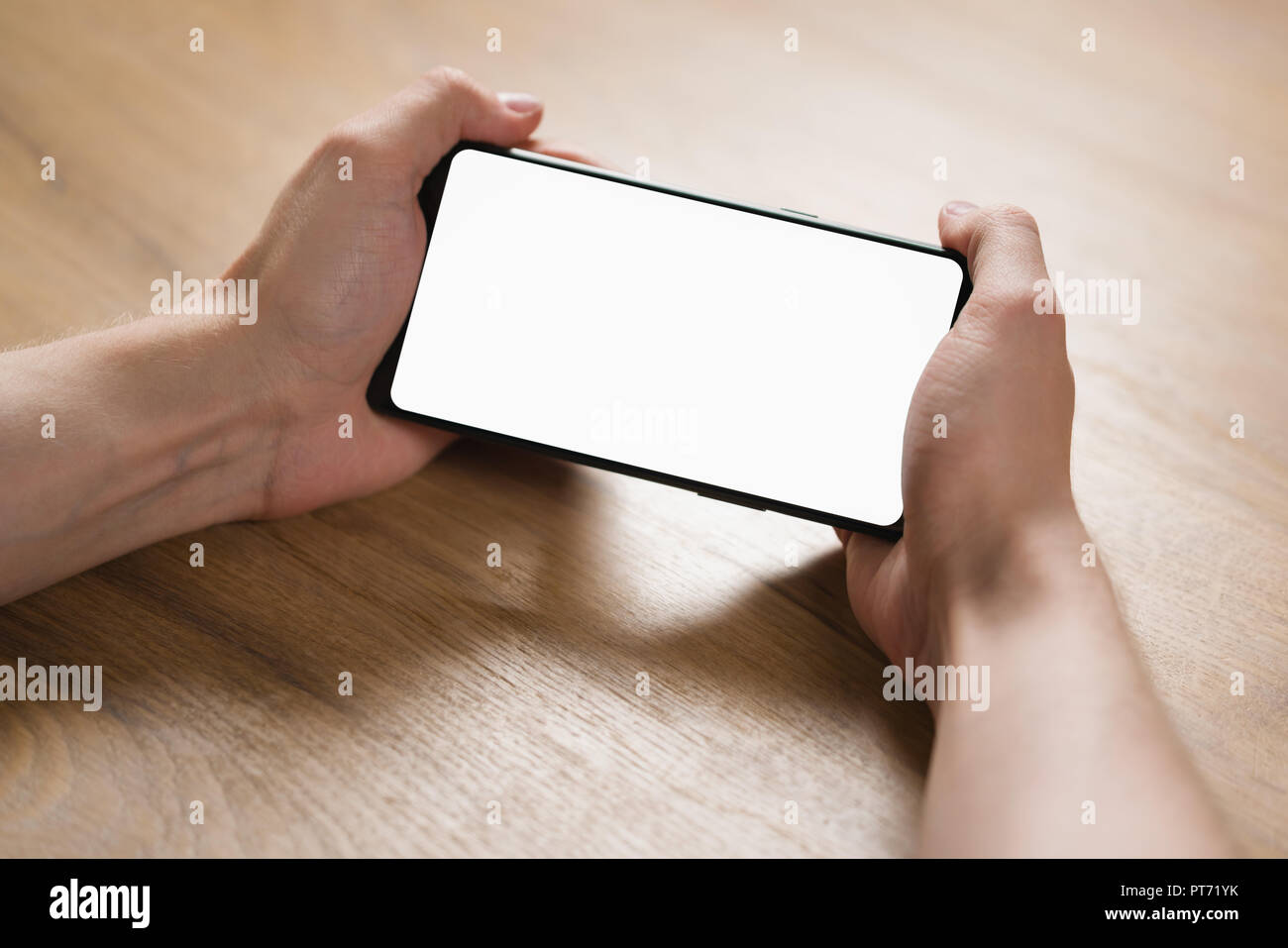 young man hands holding smartphone with blank white screen in landscape ...