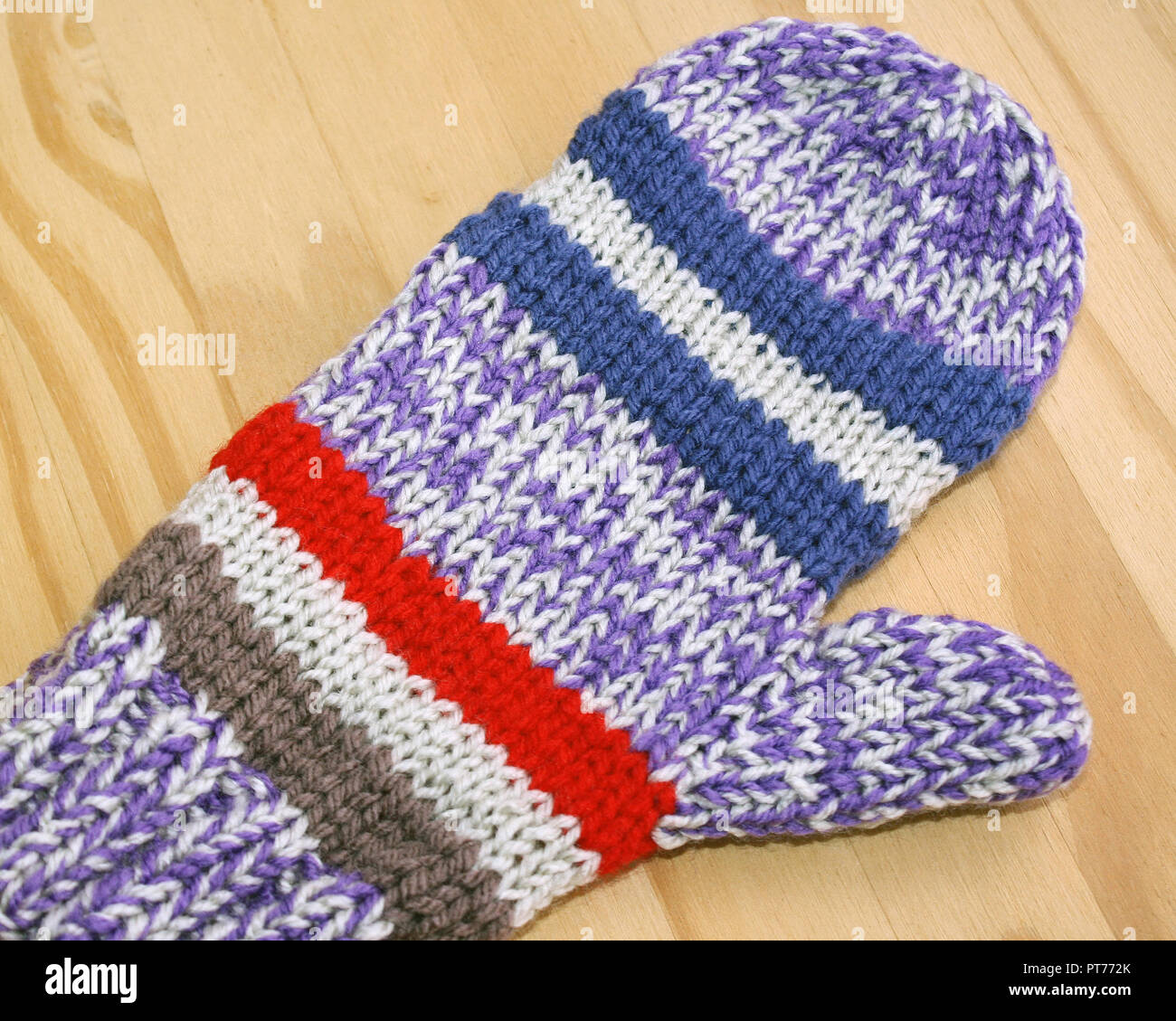 Bright and colorful handmade knitted mitten in red, purple, blue and ...
