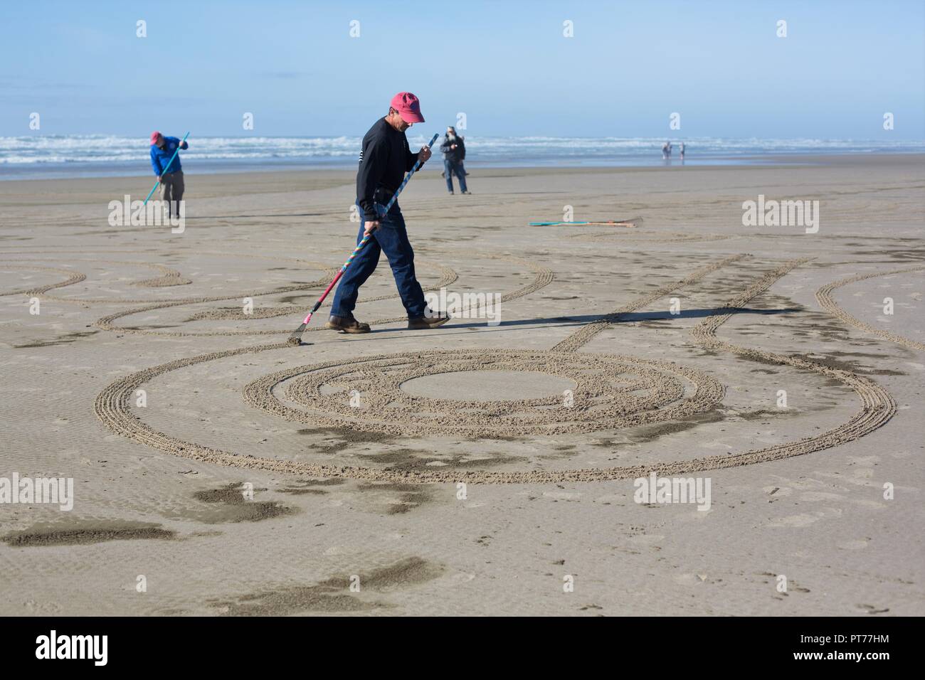A volunteer working on a large sand labyrinth created by Denny Dyke, at ...