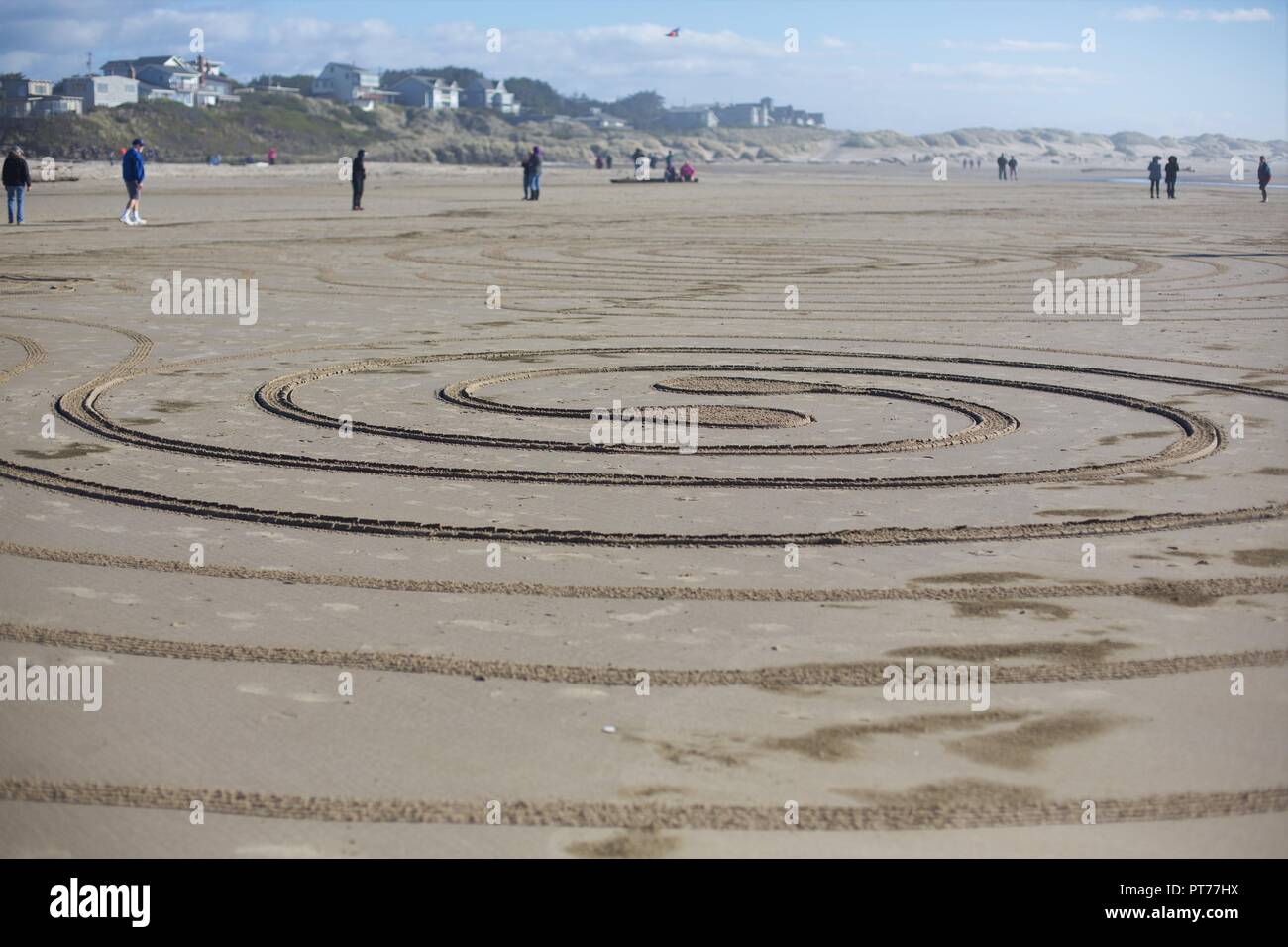 People walking a large sand labyrinth created by Denny Dyke, at Heceta ...