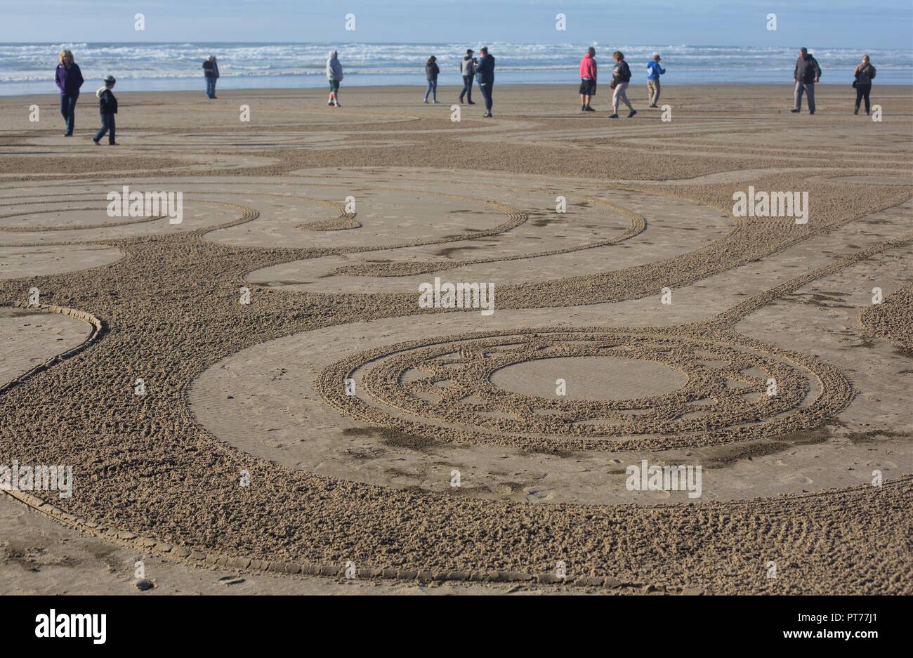 People walking a large sand labyrinth created by Denny Dyke, at Heceta ...