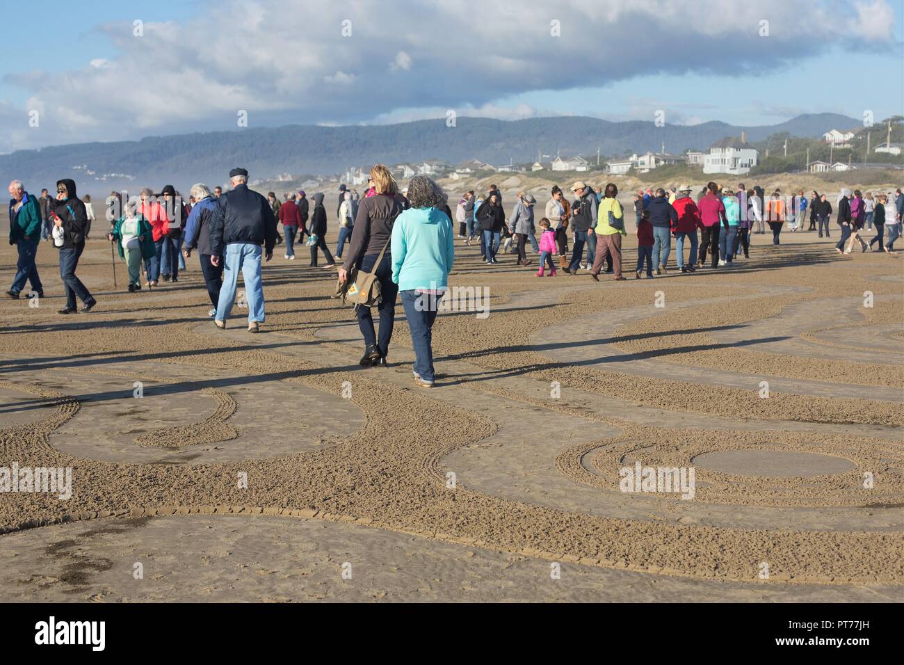 People walking a large sand labyrinth created by Denny Dyke, at Heceta ...