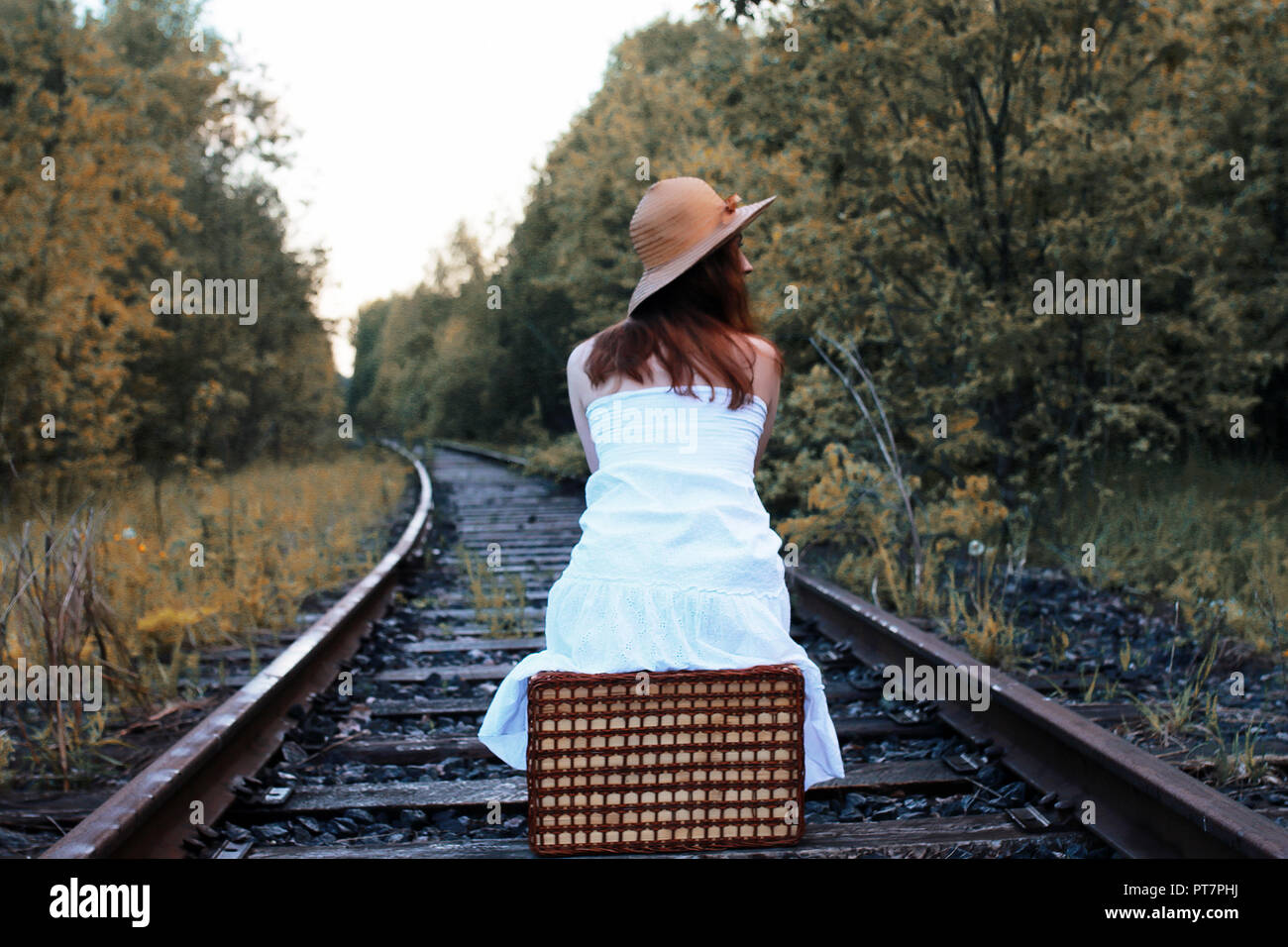 autumn park girl in white sundress and a wicker suitcase walking Stock ...