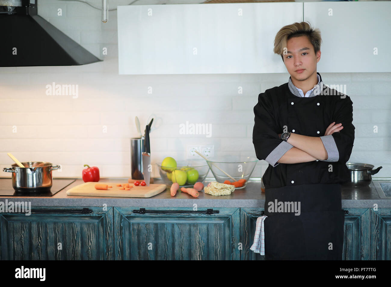 Asian cook in the kitchen prepares food in a cook suit Stock Photo - Alamy