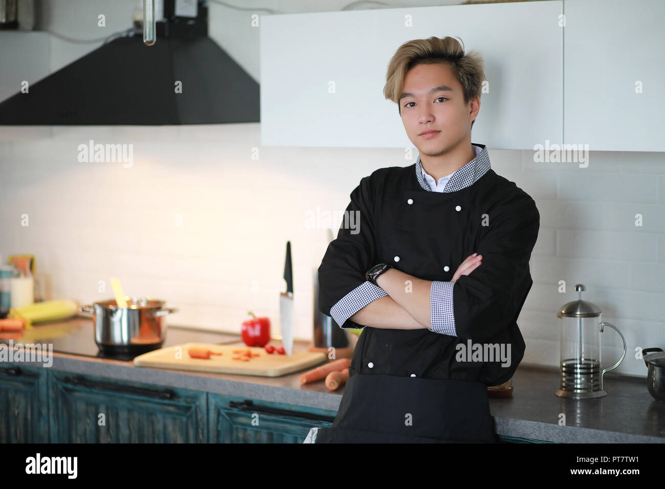 Asian cook in the kitchen prepares food in a cook suit Stock Photo - Alamy