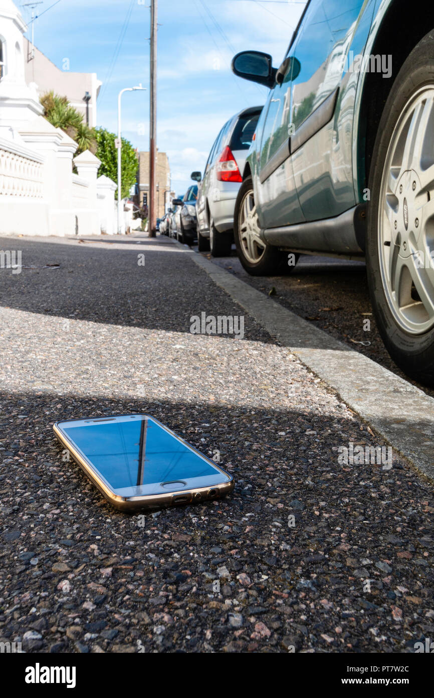 Dropped mobile phone on pavement in street. Wide angle view of ...