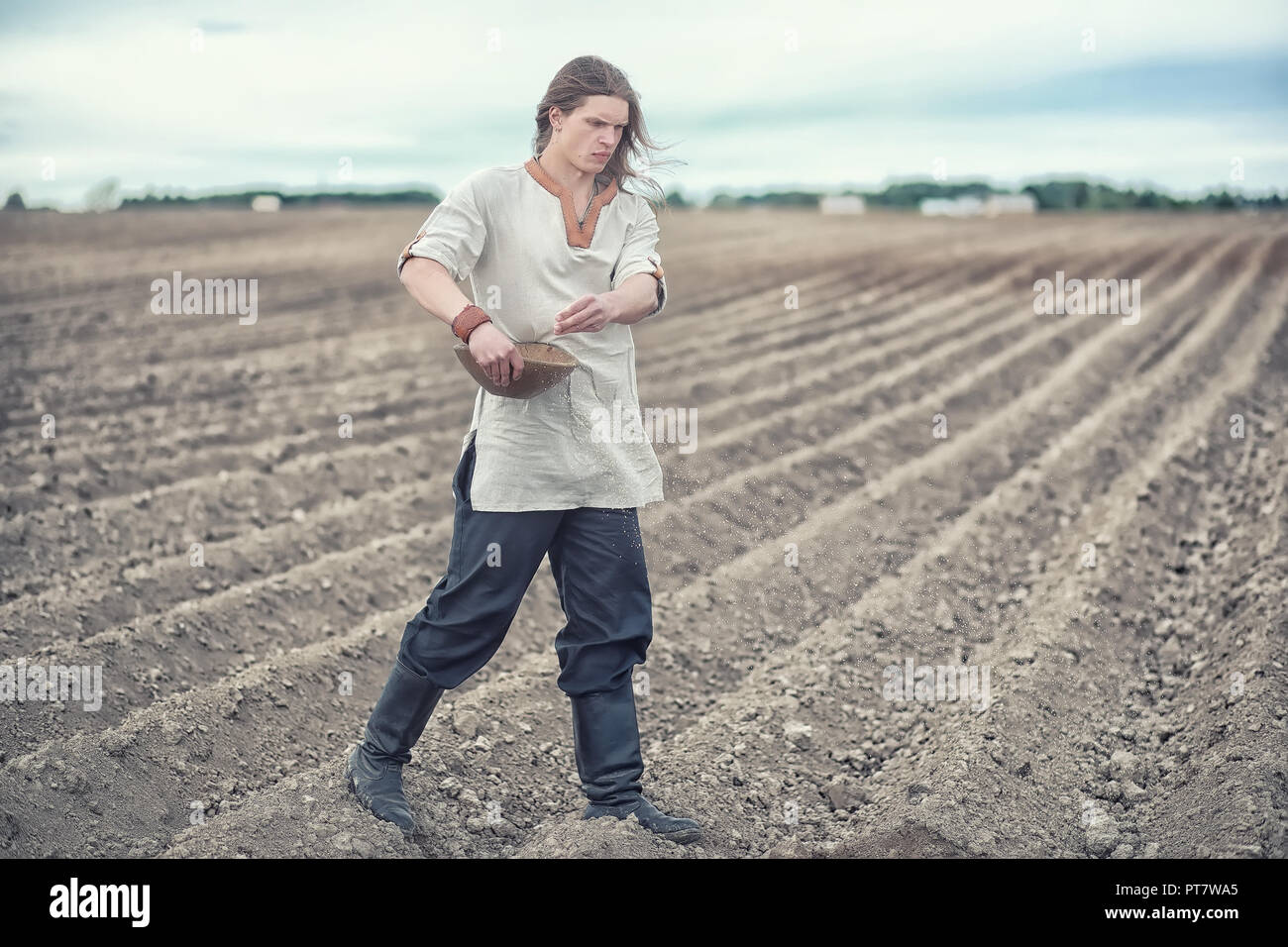 A young peasant sows the field with grain Stock Photo - Alamy