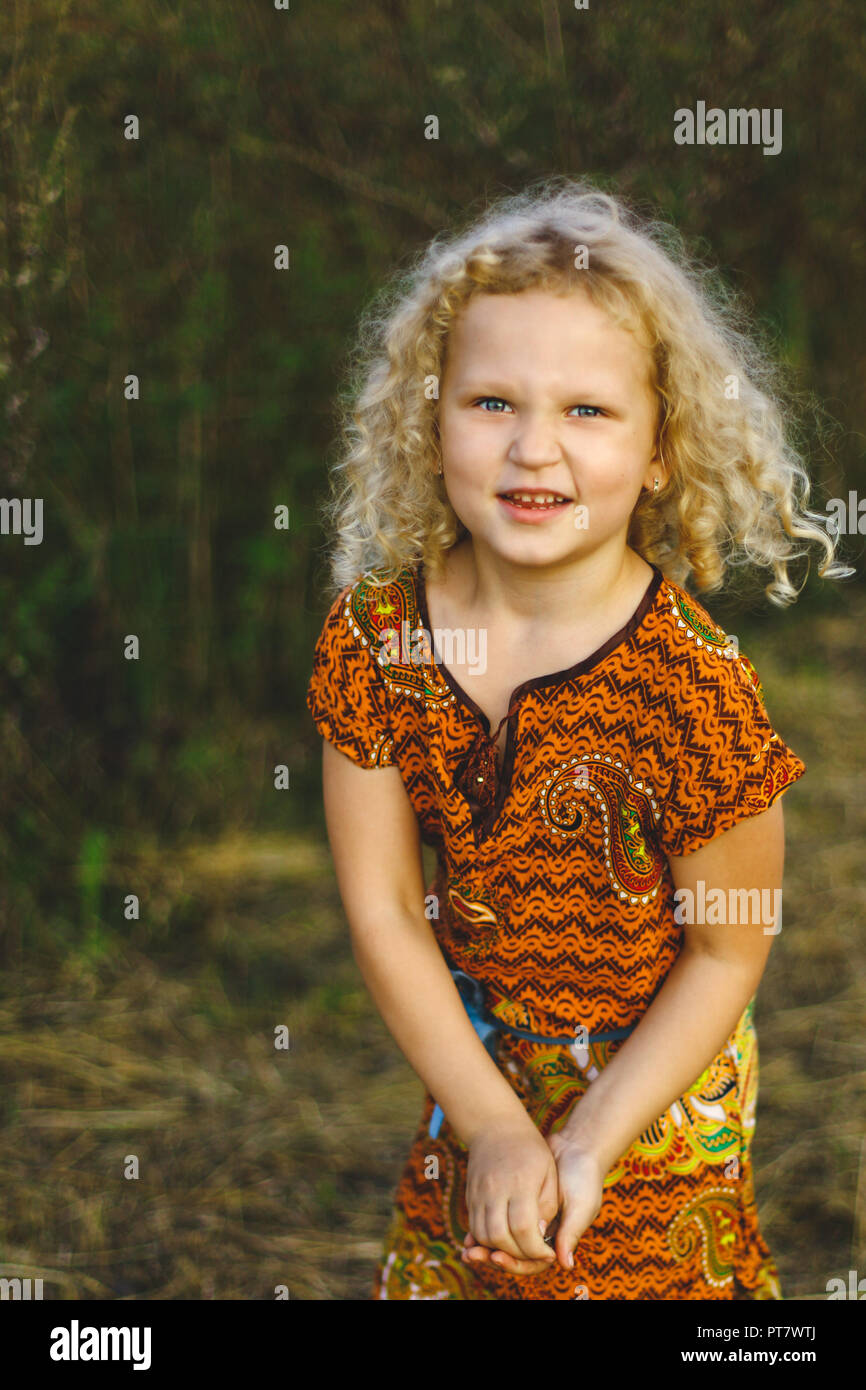little curly blonde girl playing in a field Stock Photo - Alamy
