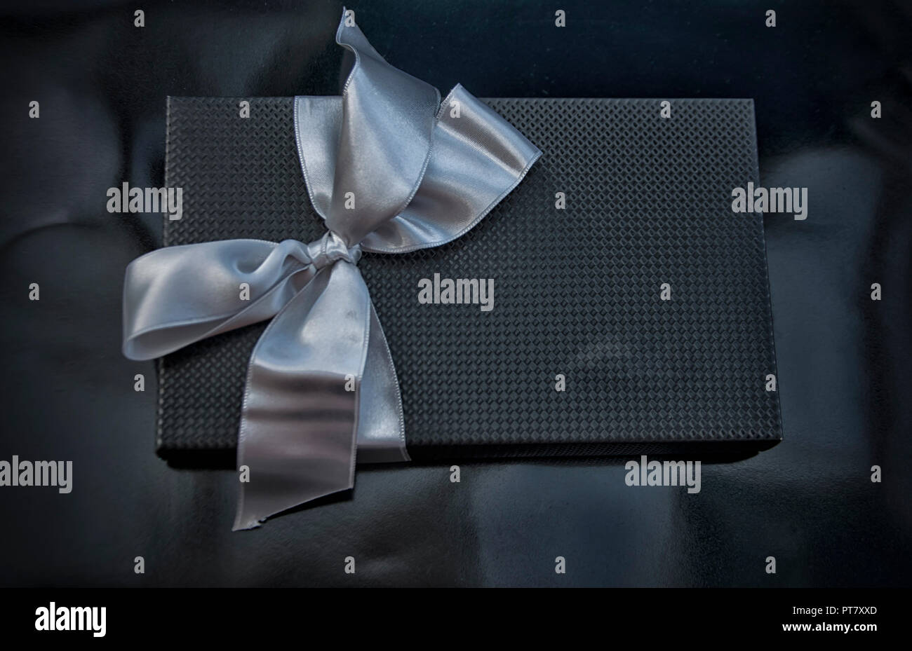 Top view of an elegant black present with a silver bow Stock Photo - Alamy