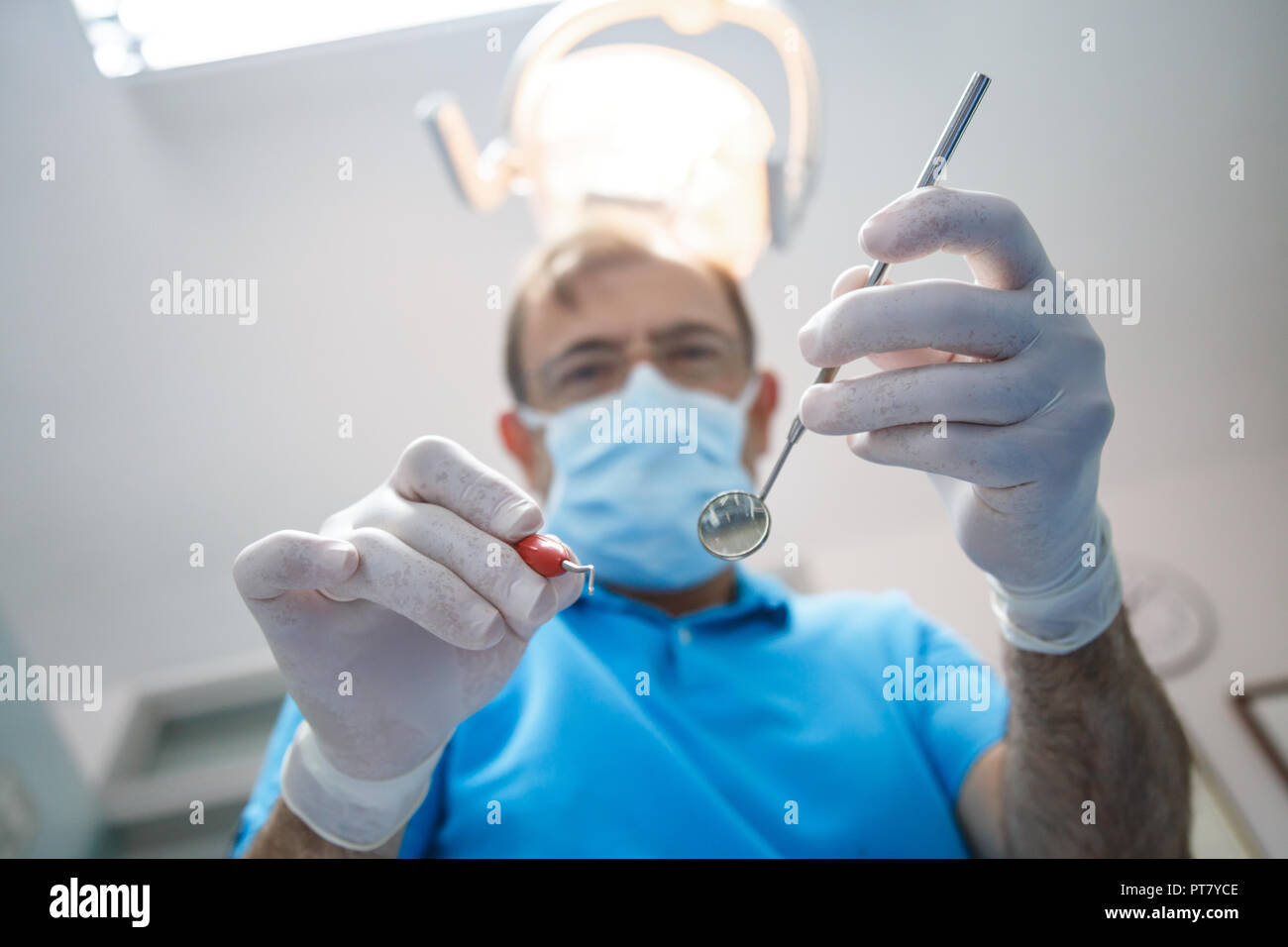 From below shot of man in uniform and gloves using tools and doing oral ...