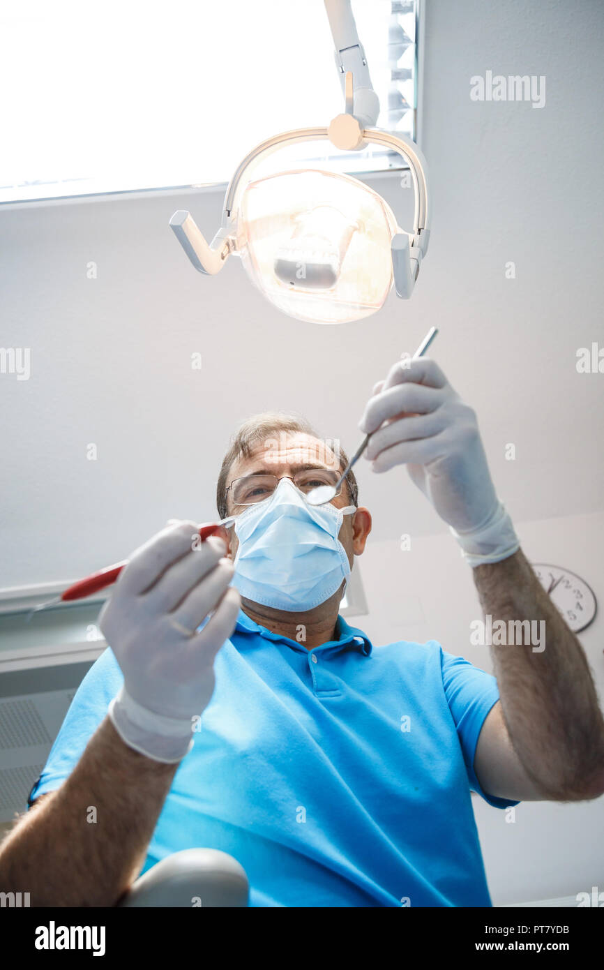 From below shot of man in uniform and gloves using tools and doing oral ...