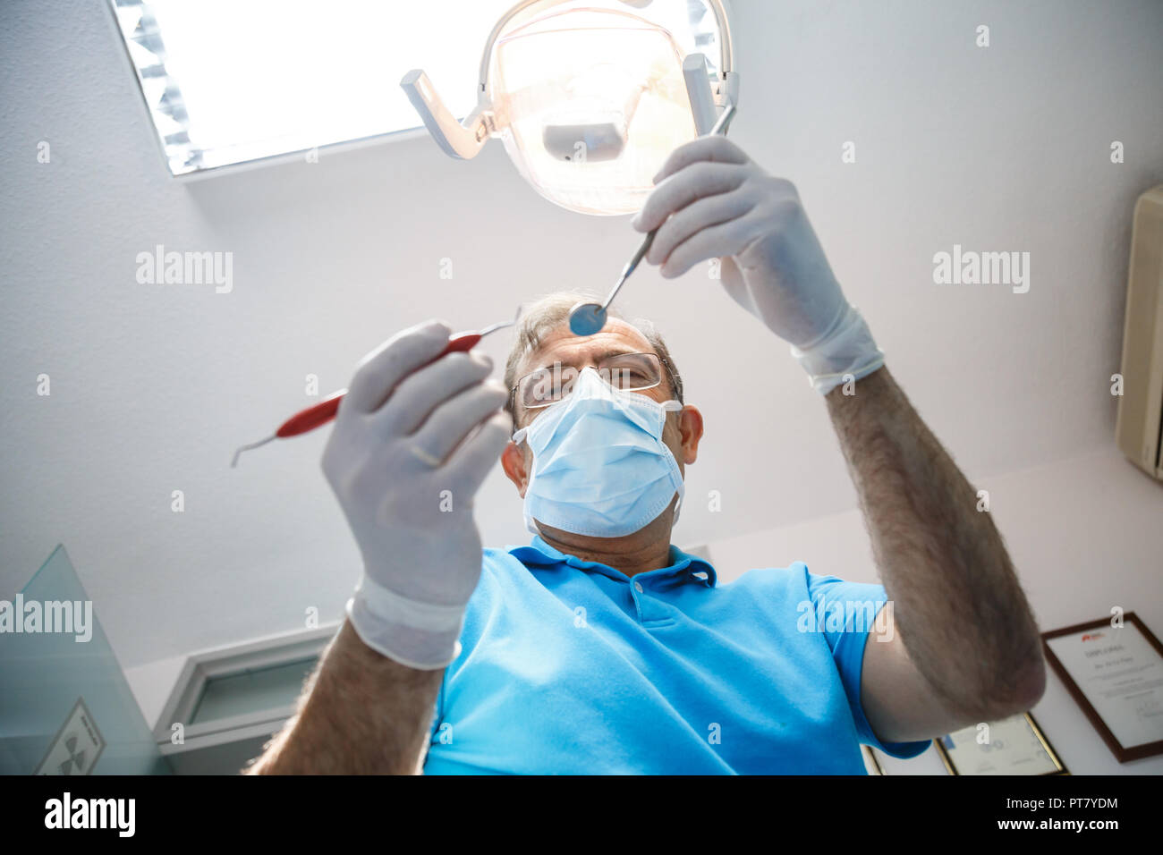 From below shot of man in uniform and gloves using tools and doing oral ...