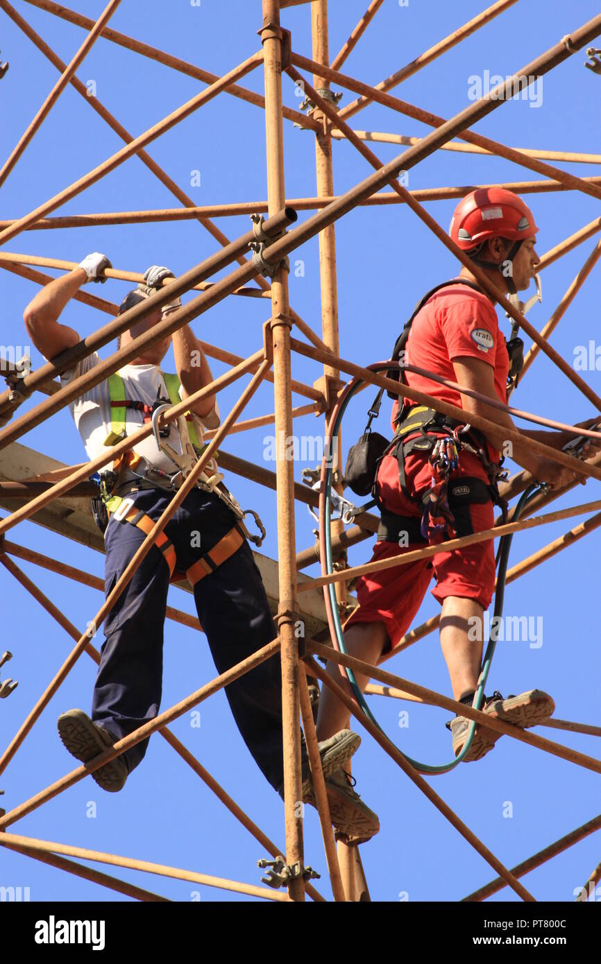 Construction workers working from scaffolding high above ground wearing ...