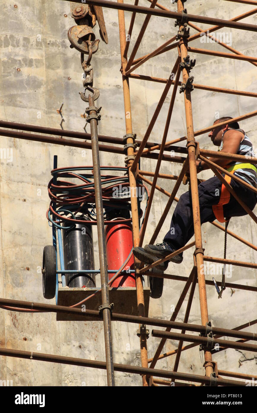 Construction workers working from scaffolding high above ground using ...