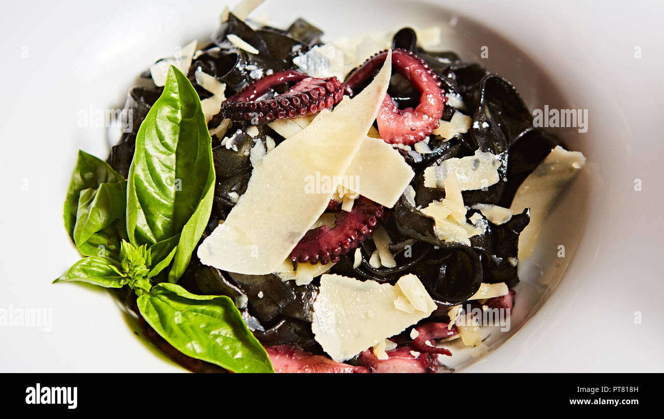 Pasta with black cuttlefish ink, octopuses and parmesan Stock Photo - Alamy