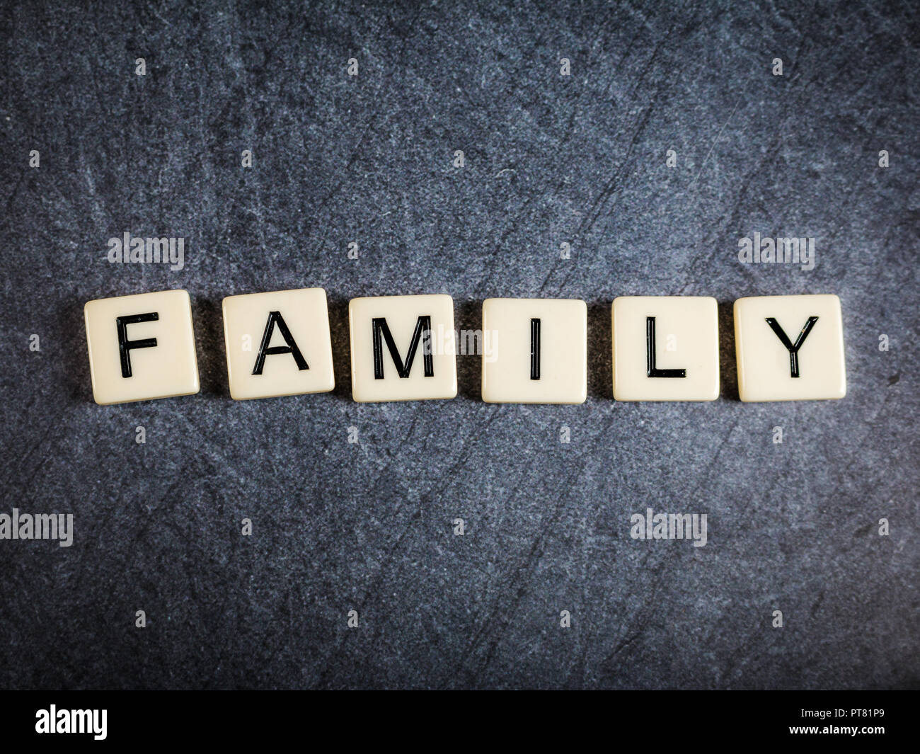 Letter tiles on black slate background spelling Family Stock Photo - Alamy