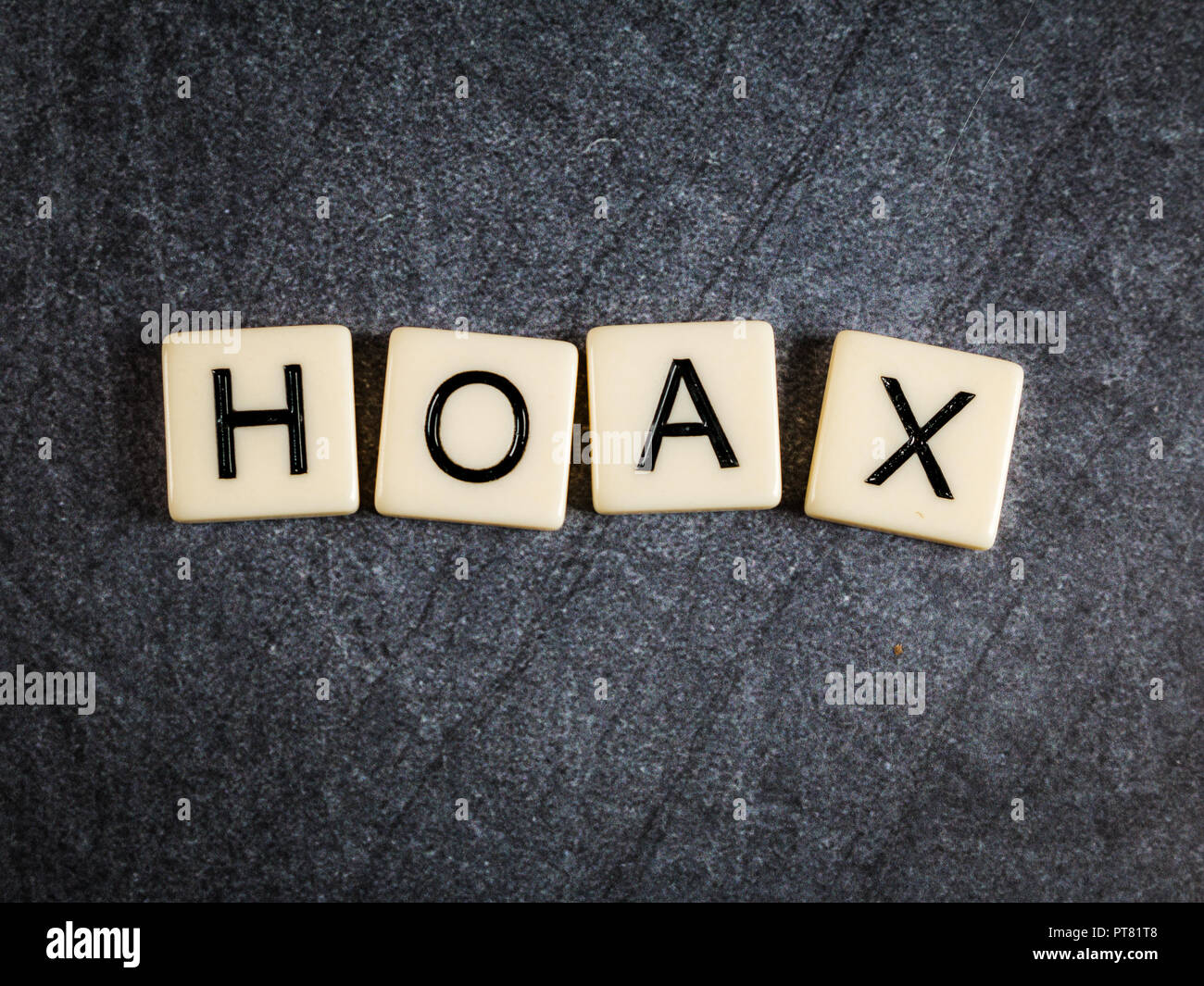 Letter tiles on black slate background spelling Hoax Stock Photo - Alamy