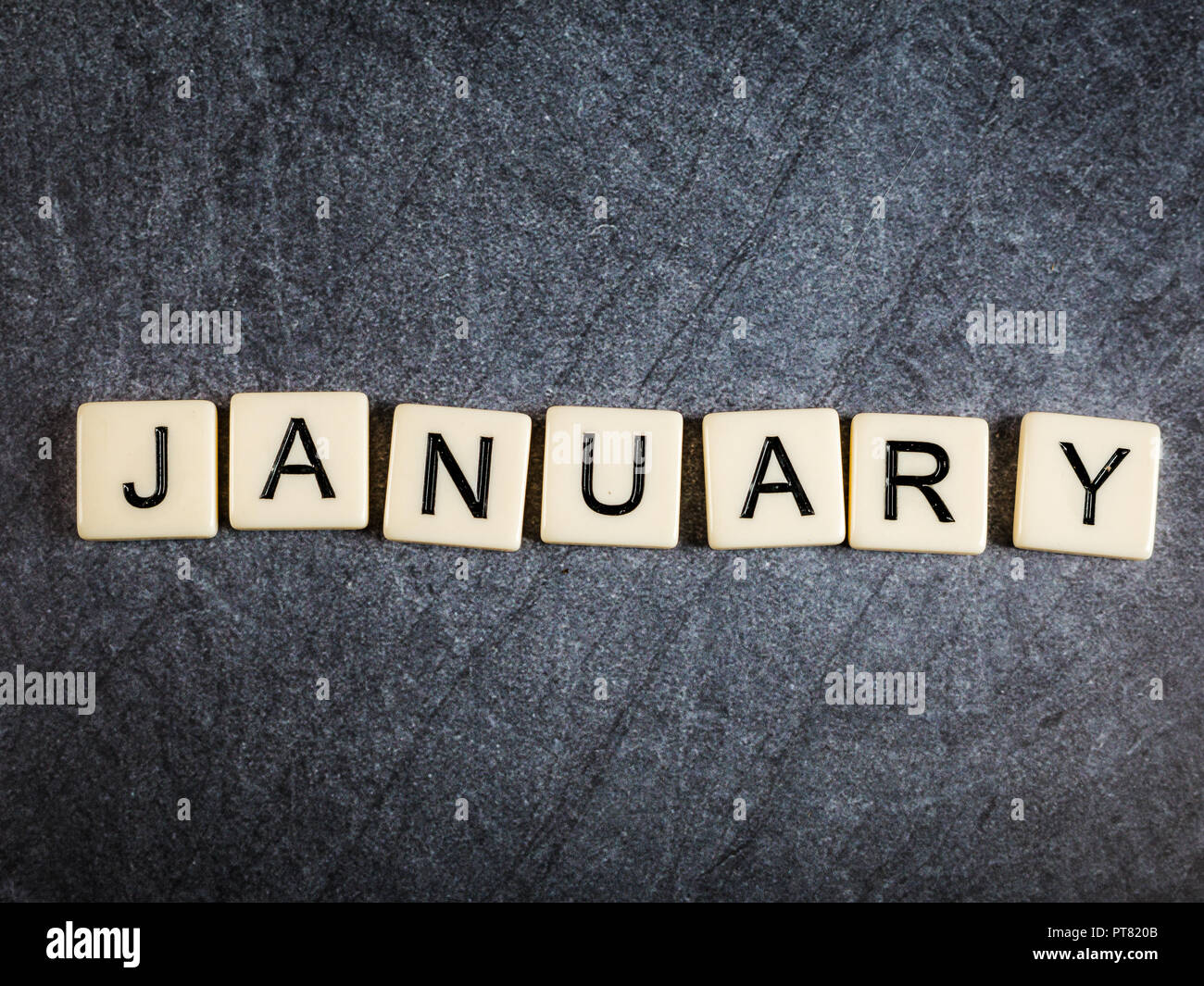Letter tiles on black slate background spelling January Stock Photo - Alamy