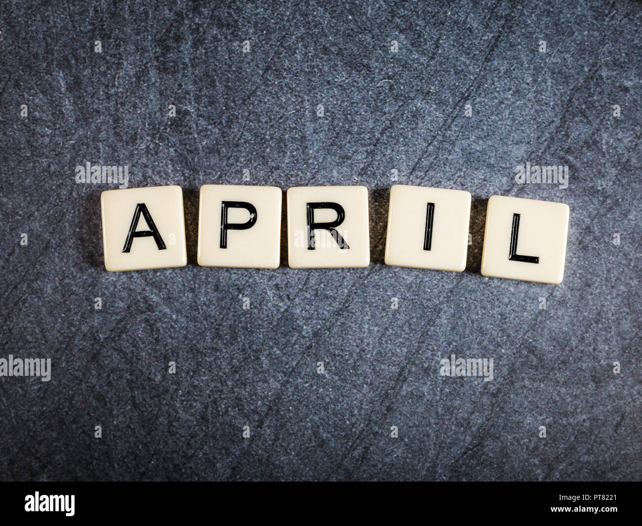 Letter tiles on black slate background spelling April Stock Photo - Alamy