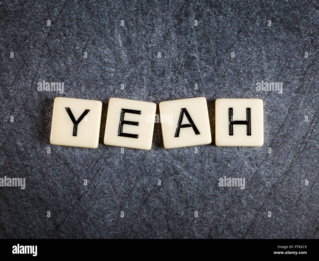 Letter tiles on black slate background spelling Yeah Stock Photo - Alamy