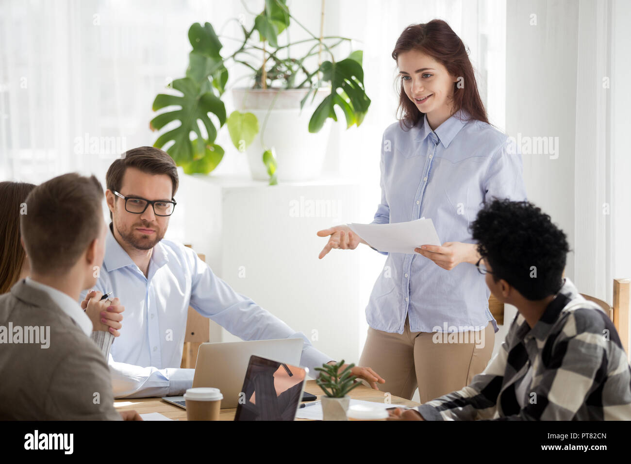 Worker woman presenting report to colleagues in office Stock Photo - Alamy