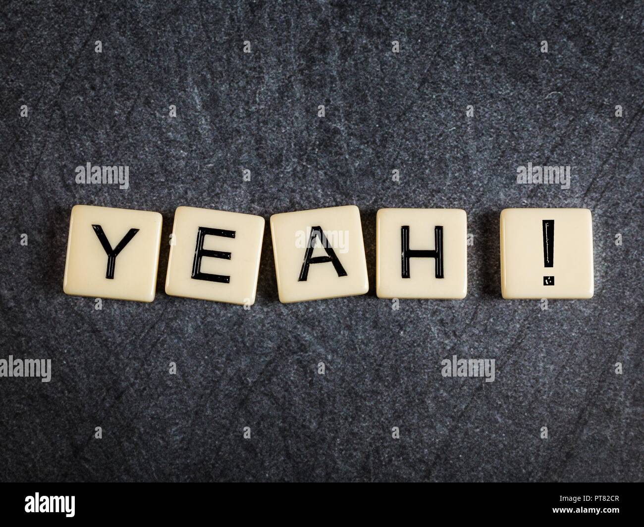 Letter tiles on black slate background spelling Yeah! Stock Photo - Alamy