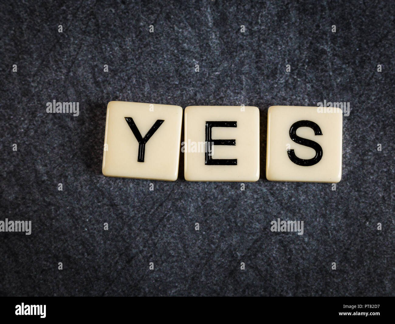 Letter tiles on black slate background spelling Yes Stock Photo - Alamy