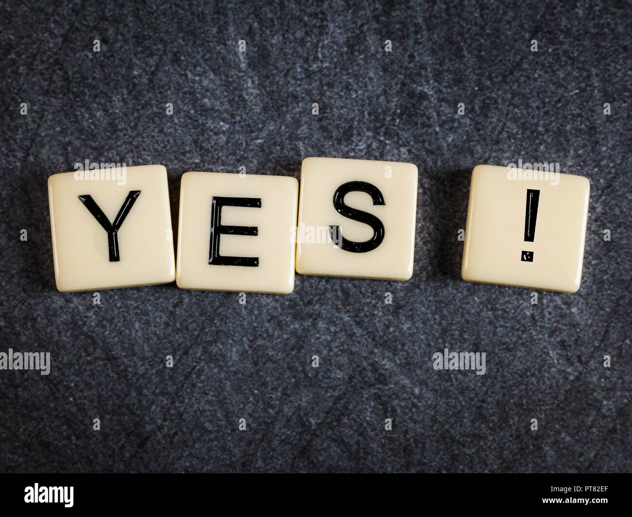 Letter tiles on black slate background spelling Yes! Stock Photo - Alamy