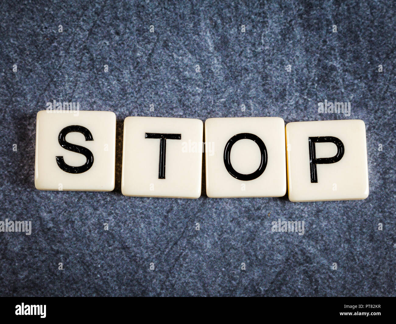 Letter tiles on black slate background spelling Stop Stock Photo - Alamy