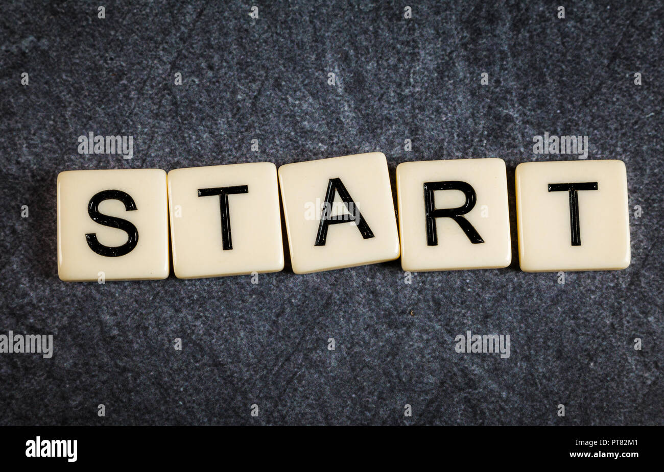 Letter tiles on black slate background spelling Start Stock Photo - Alamy