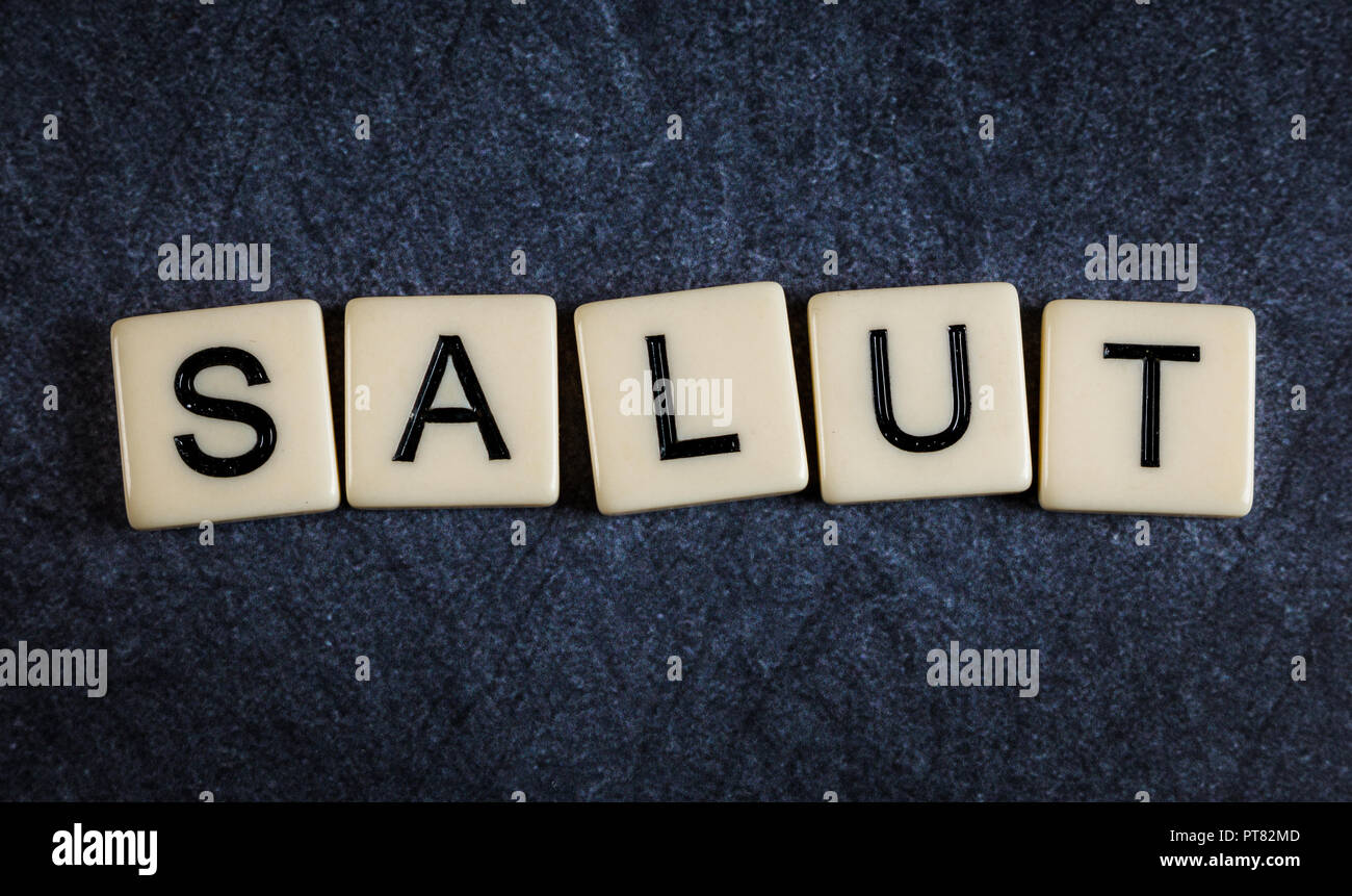 Letter tiles on black slate background spelling Salut Stock Photo - Alamy
