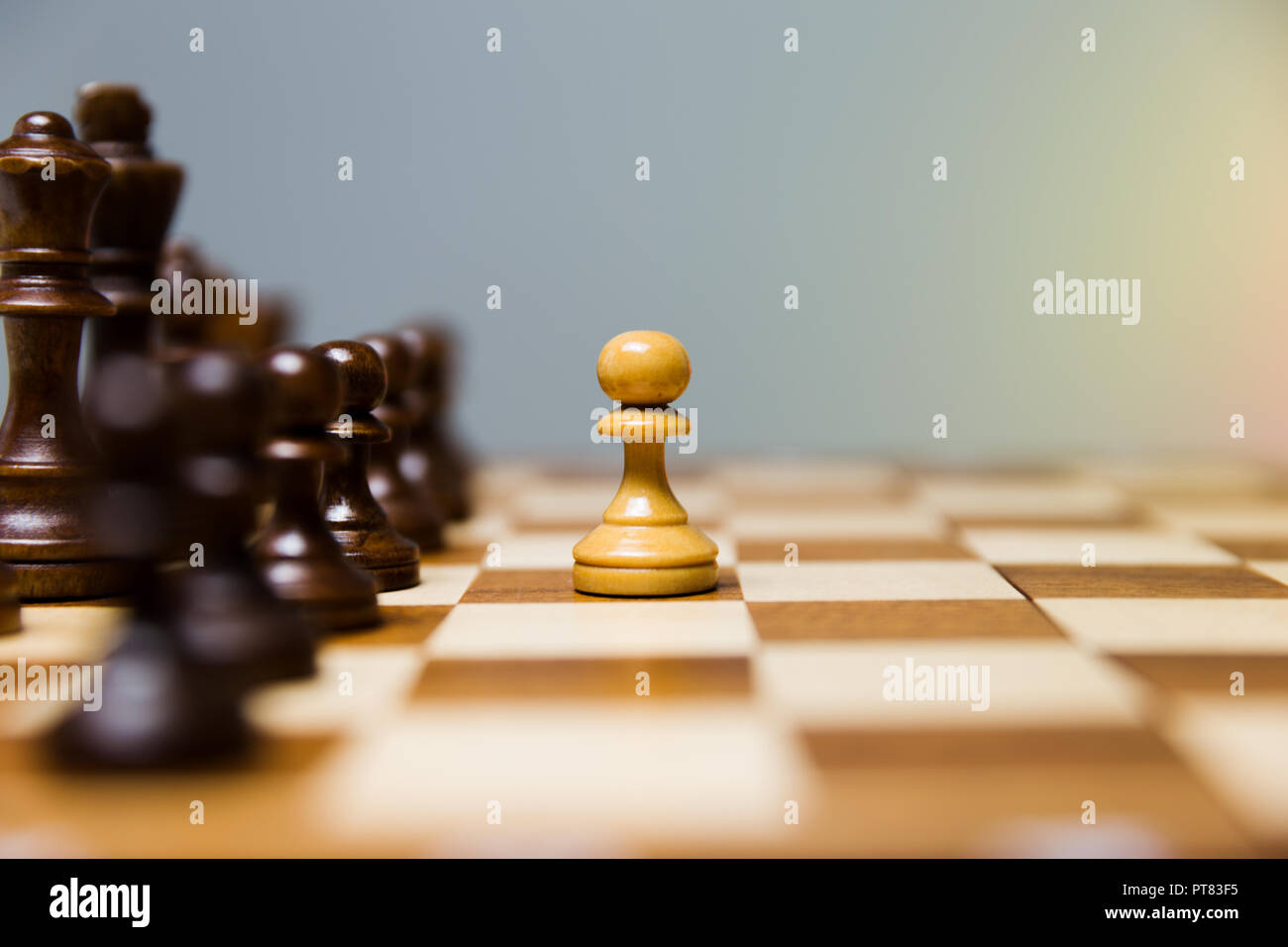 Pawn standing in front of aligned dark chess figures. Courage and ...