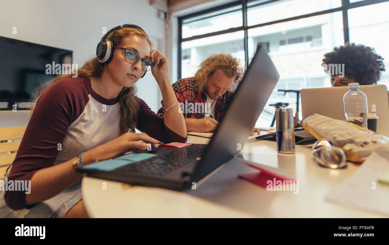 Female tech professional working on laptop with colleagues working at ...