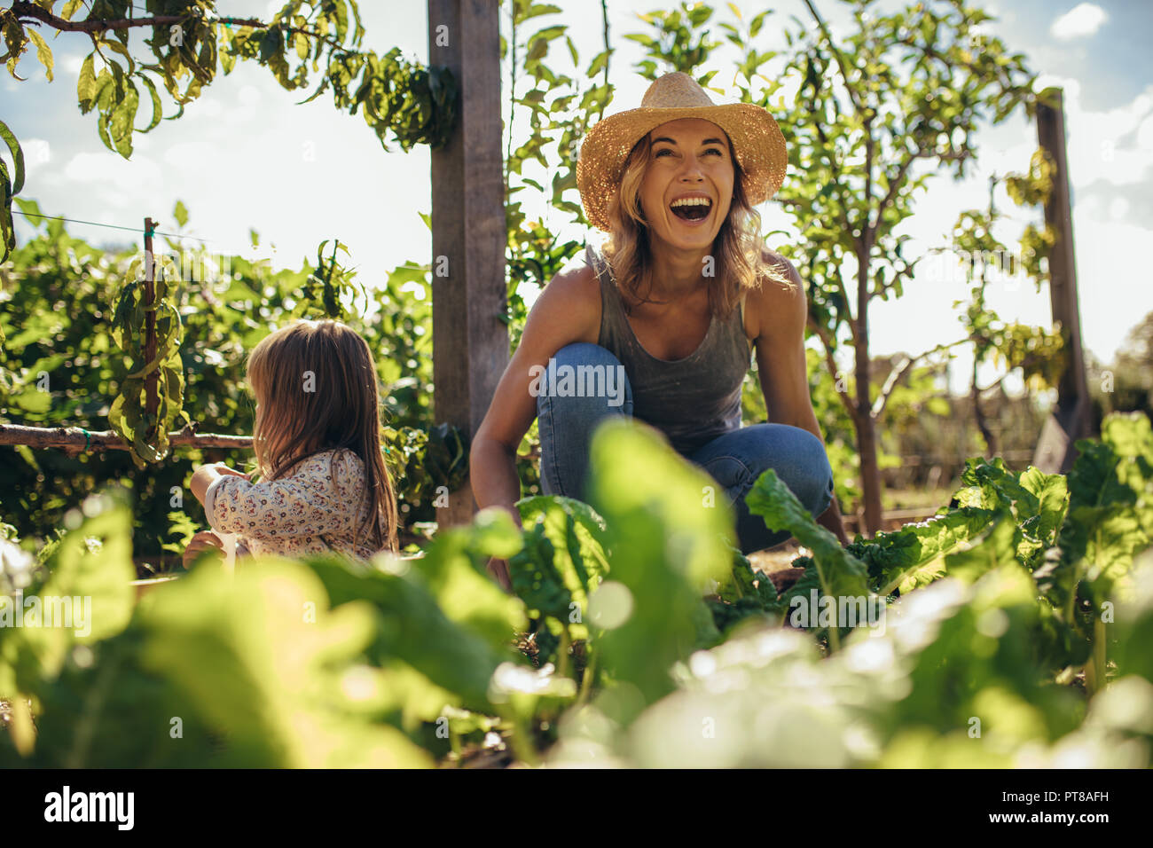 Beautiful young female farmer working in her garden with her daughter ...