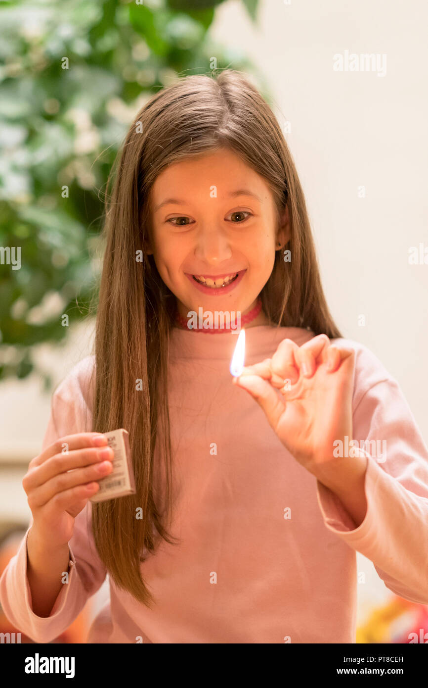 Girl playing with matches. Dangerous situation at home. A small child ...