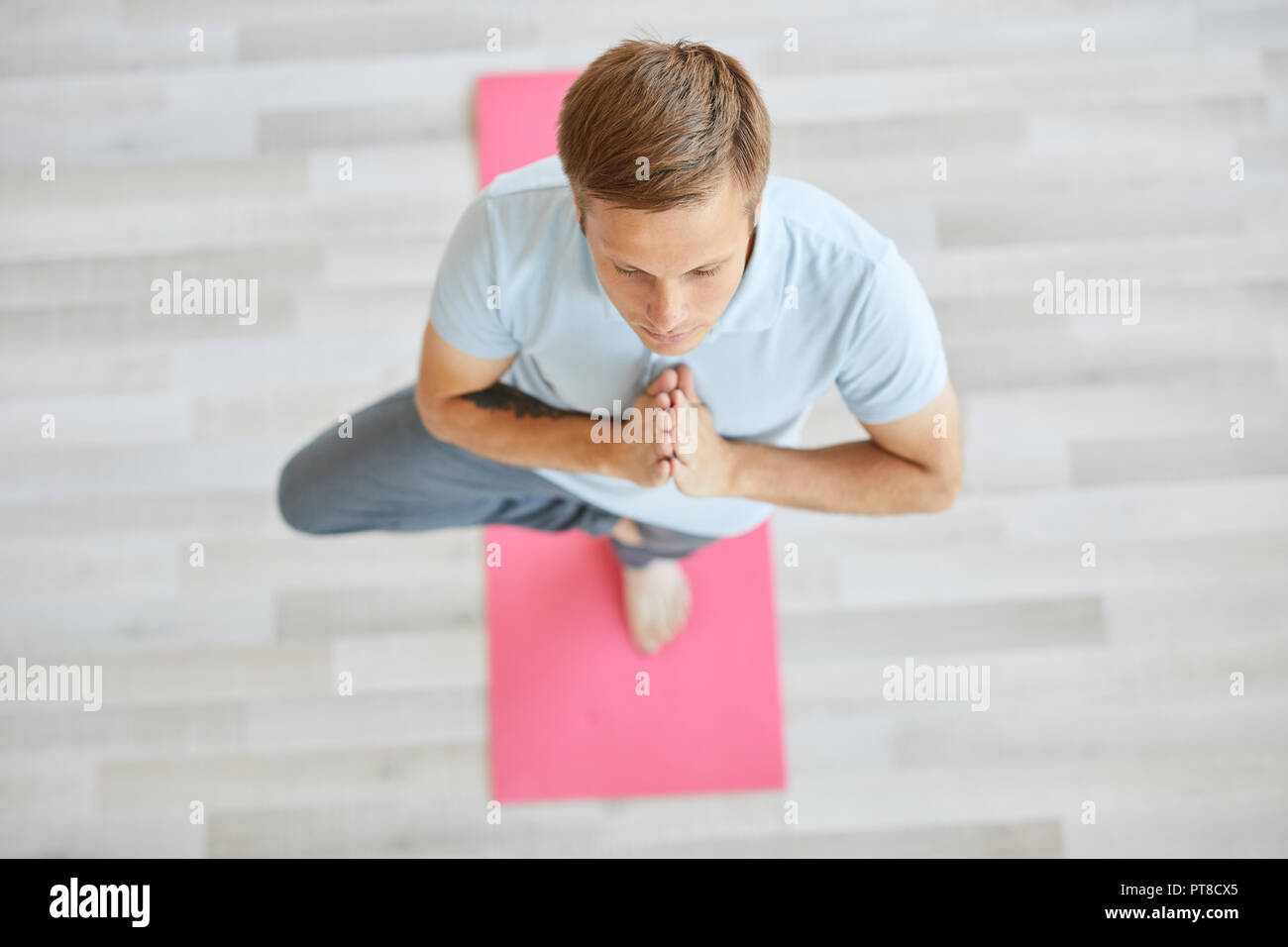 View of young active man standing on one leg with his hands put ...