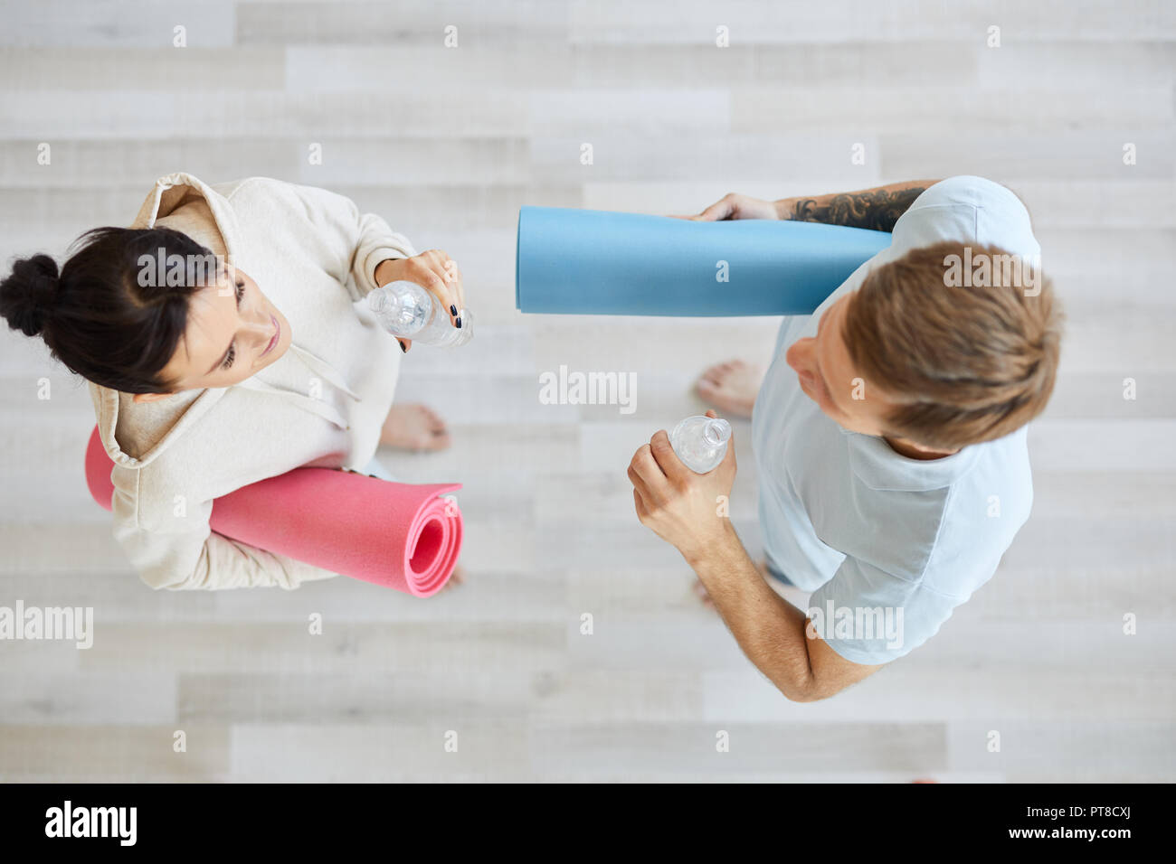 Overview of active couple with bottles of water having refreshment ...
