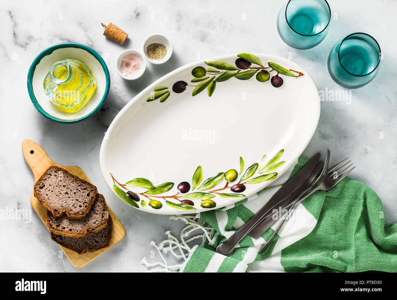 Empty handmade oval dish with olive tree branches on a white marble ...