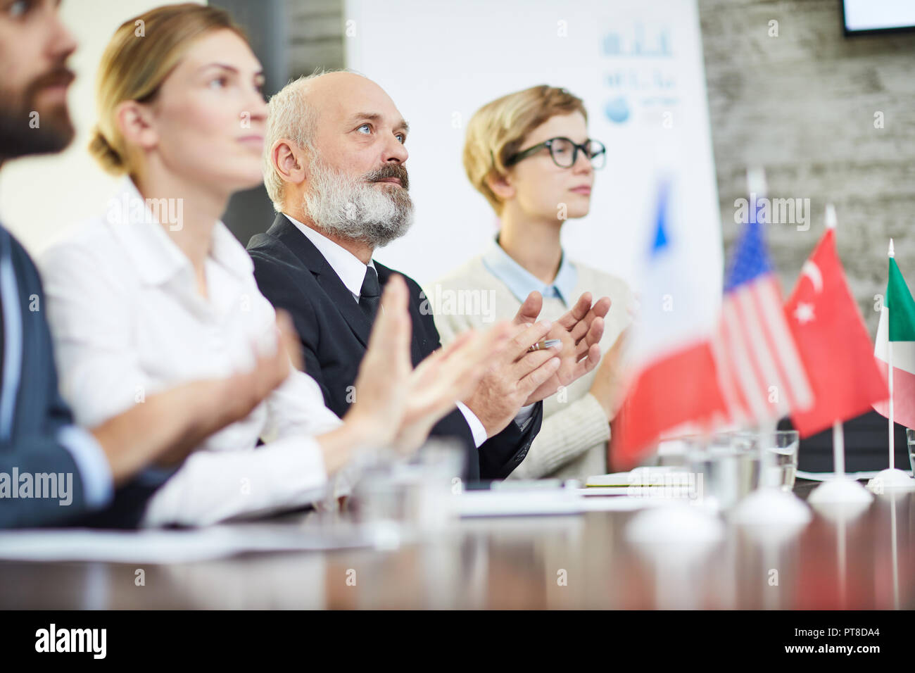 Senior politician and his young foreign colleagues applauding to one of ...