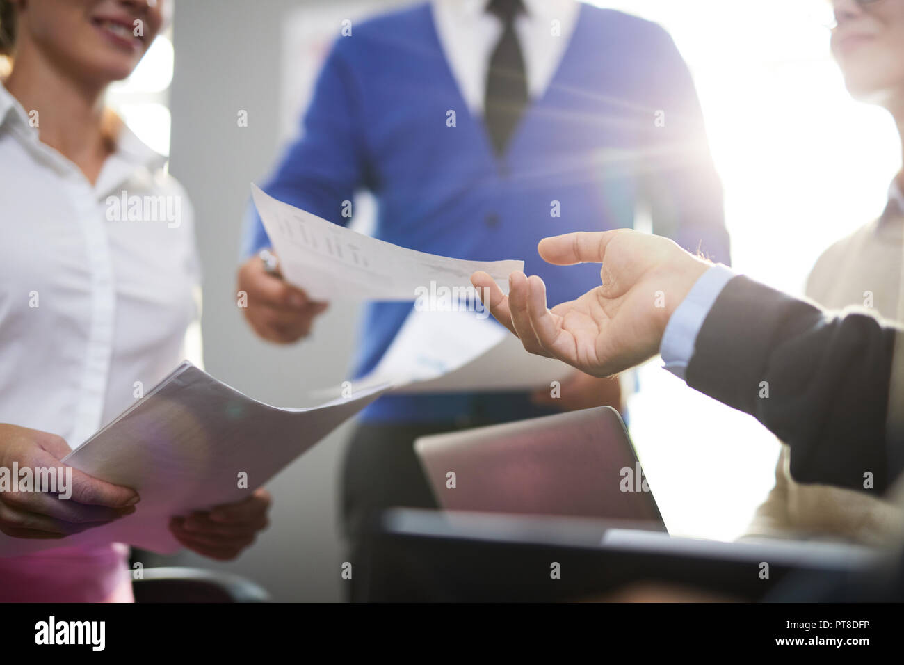 Businessman passing paper over to one of colleagues while discussing ...