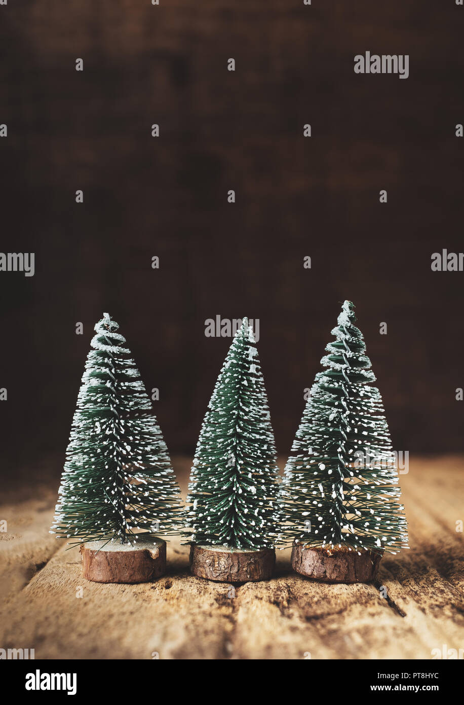Three mini christmas tree wood on rustic wooden table and dark brown ...
