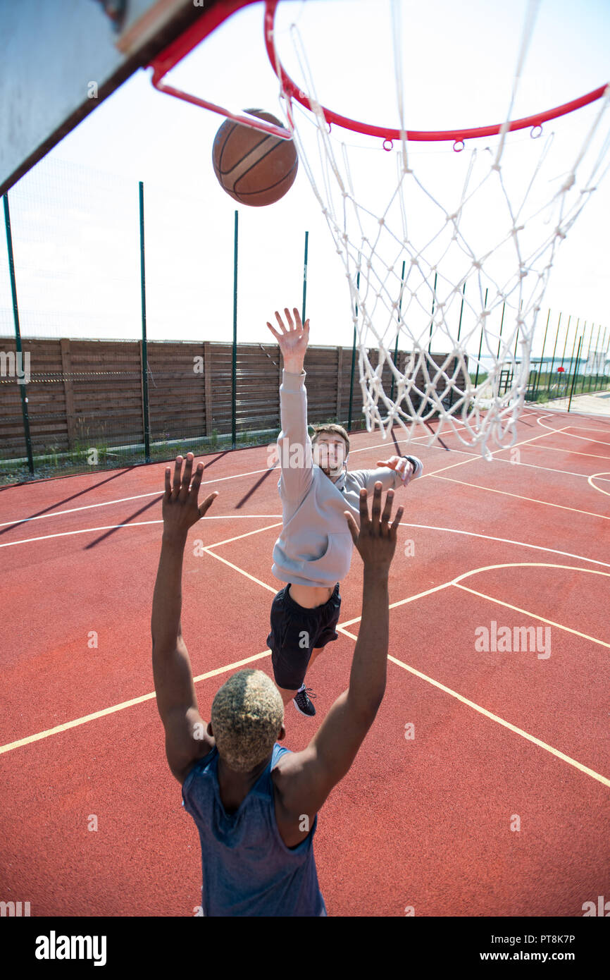 High angle view of two young men playing basketball and jumping by hoop ...