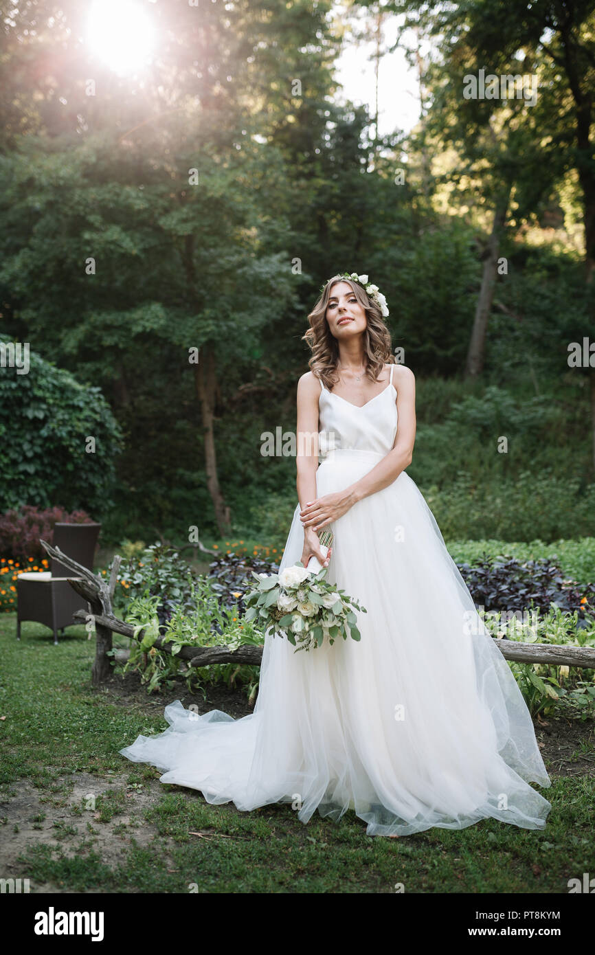 Beautiful blonde happy bride in elegant white dress in a wreath with ...