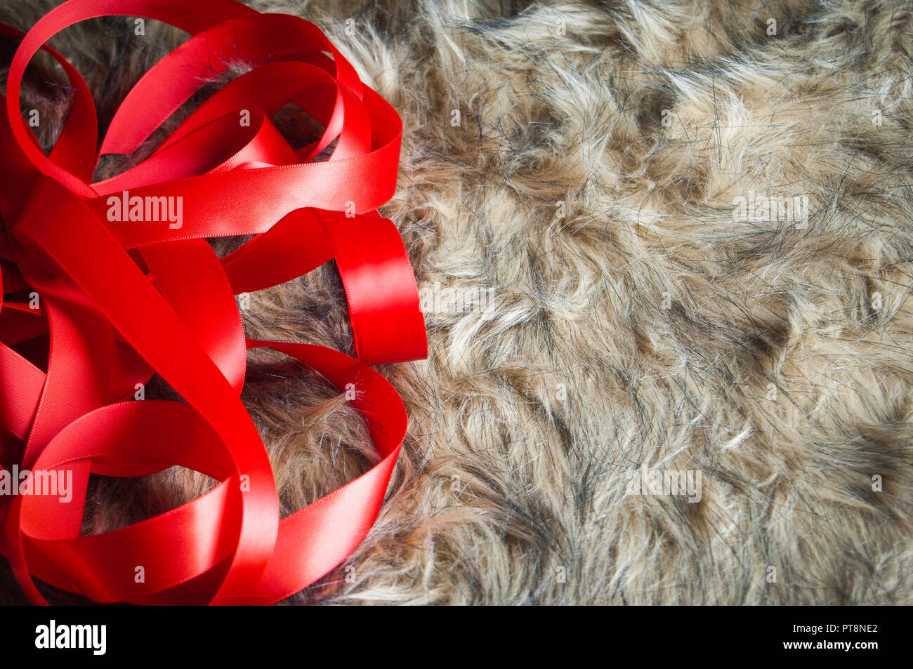 An artful swirl of shiny red satin ribbon set on the left side of a ...