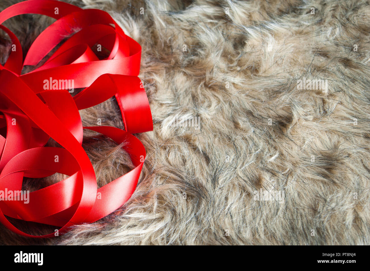 An artful swirl of shiny red satin ribbon set on the left side of a ...
