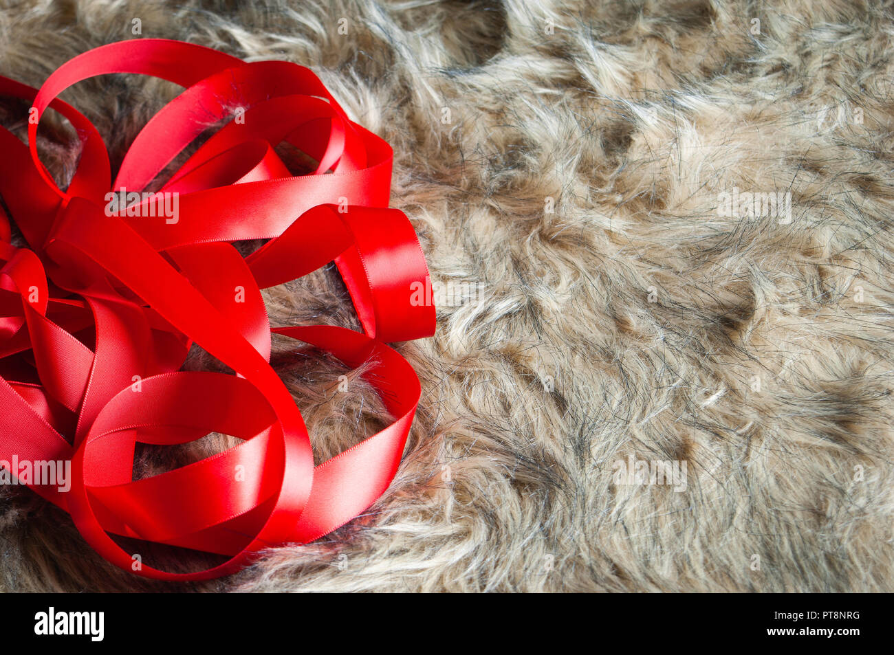 An artful swirl of shiny red satin ribbon set on the left side of a ...