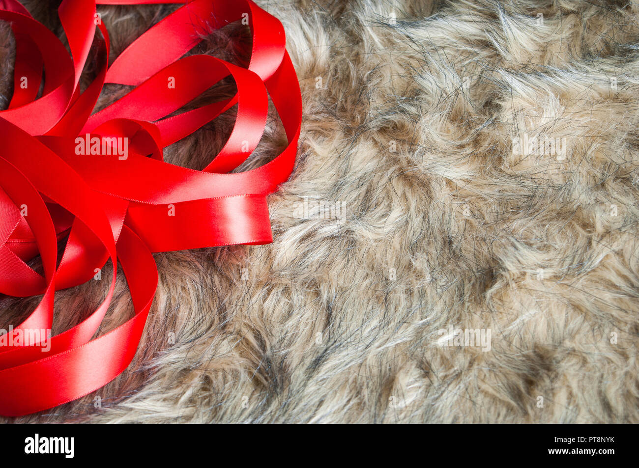 An artful swirl of shiny red satin ribbon set on the left side of a ...