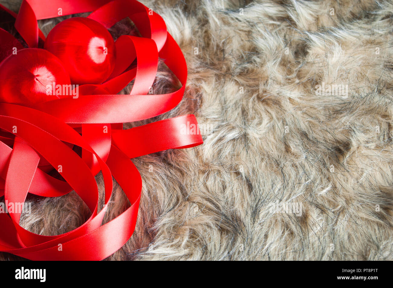 A swirl of shiny red satin ribbon with two shiny red balls set on the ...